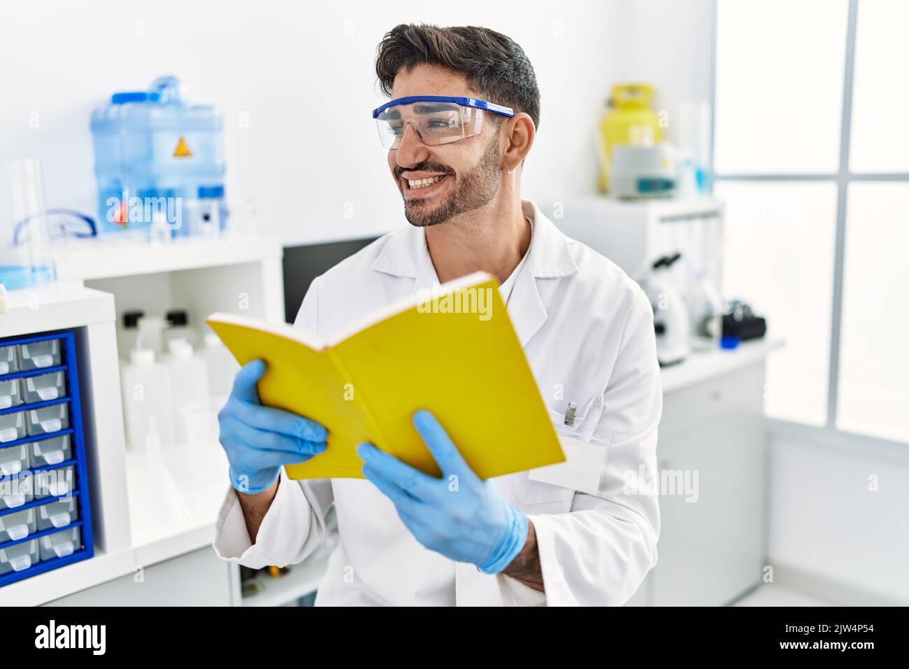 Handsome hispanic man working as scientific reading a book at ...