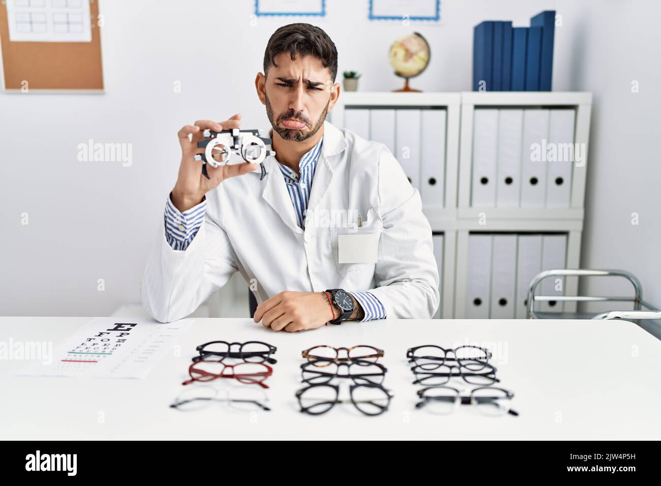 Young optician man holding optometry glasses depressed and worry for ...