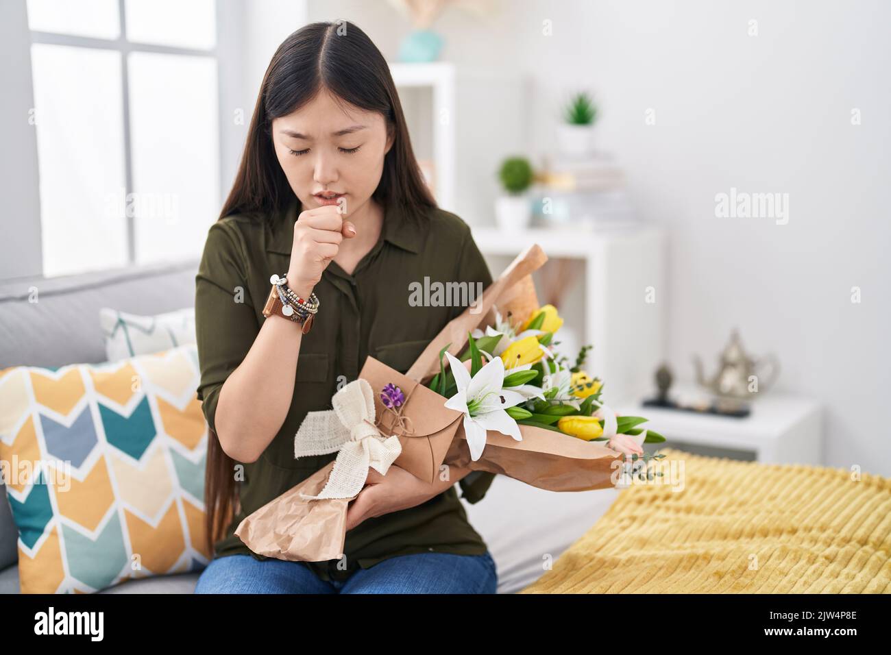 Chinese young woman holding bouquet of white flowers feeling unwell and ...