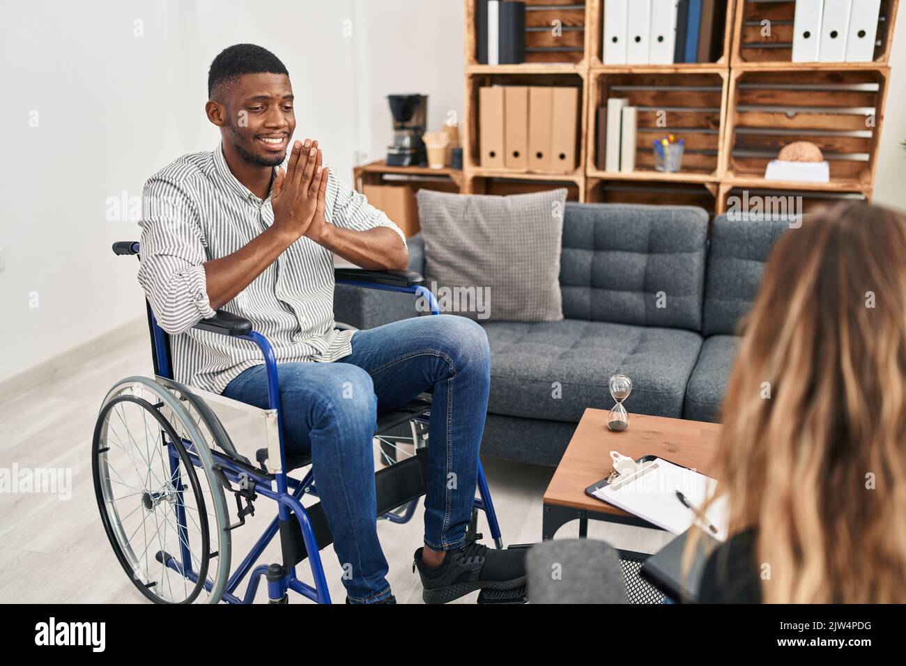 African american man doing therapy sitting on wheelchair praying with ...