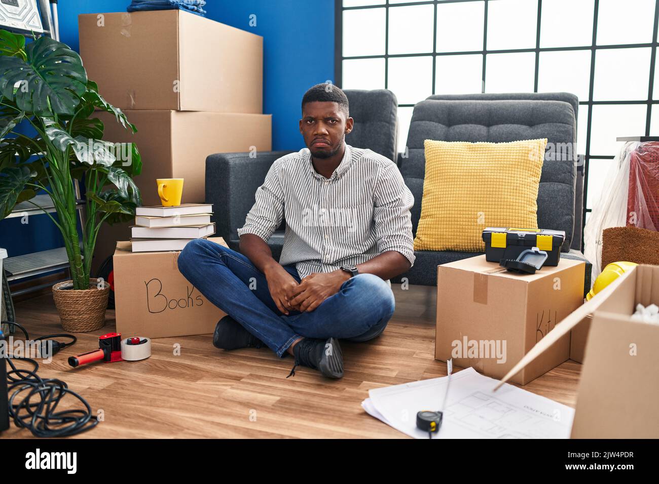 African american man sitting on the floor at new home depressed and ...