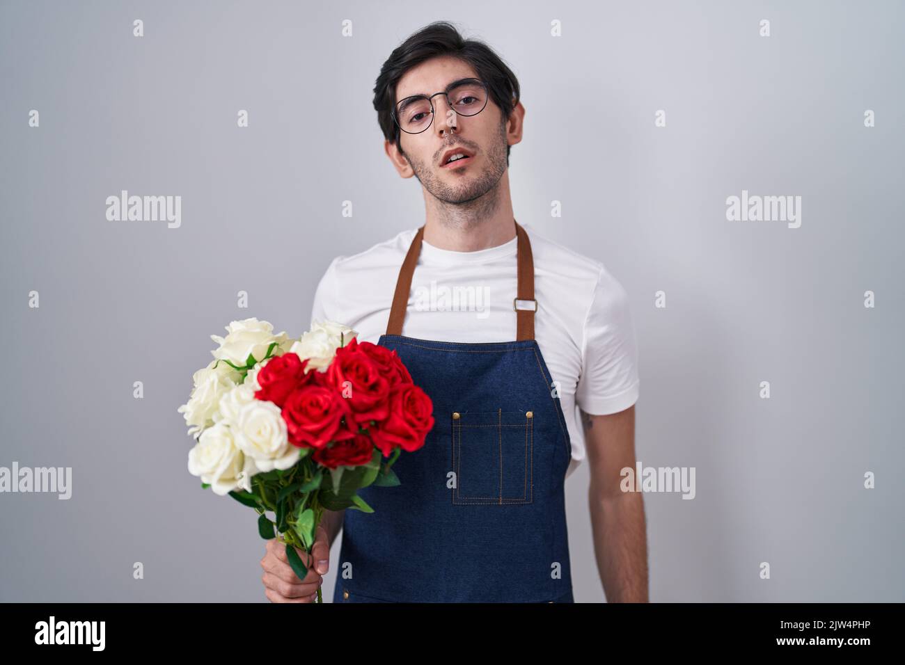 Young hispanic man holding bouquet of white and red roses looking ...