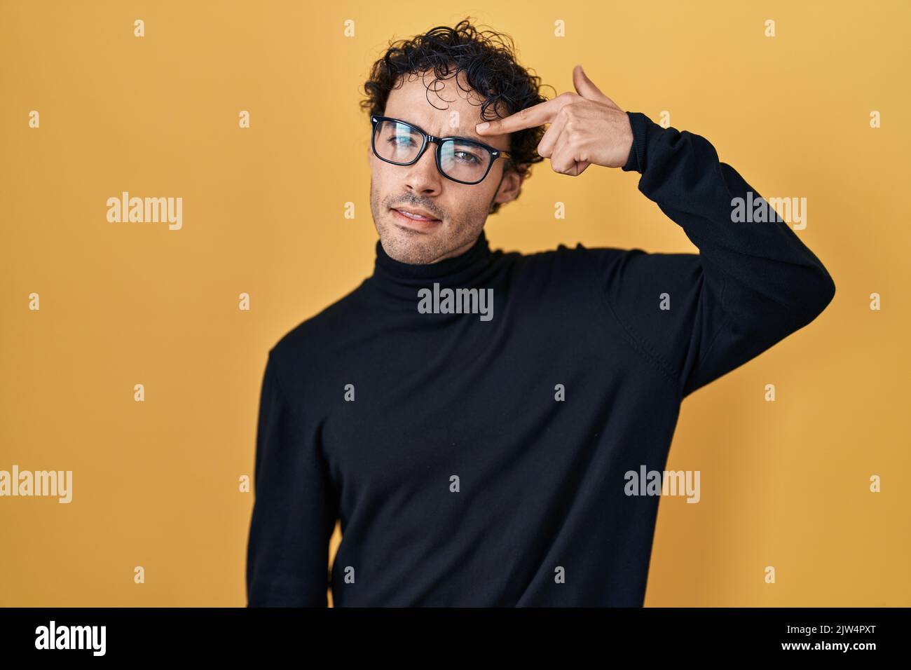 Hispanic man standing over yellow background pointing unhappy to pimple ...