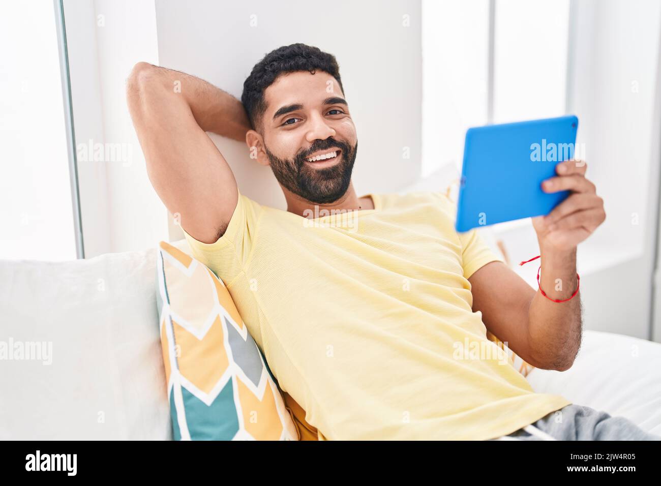Young arab man watching video on touchpad sitting on bed at bedroom Stock Photo - Alamy