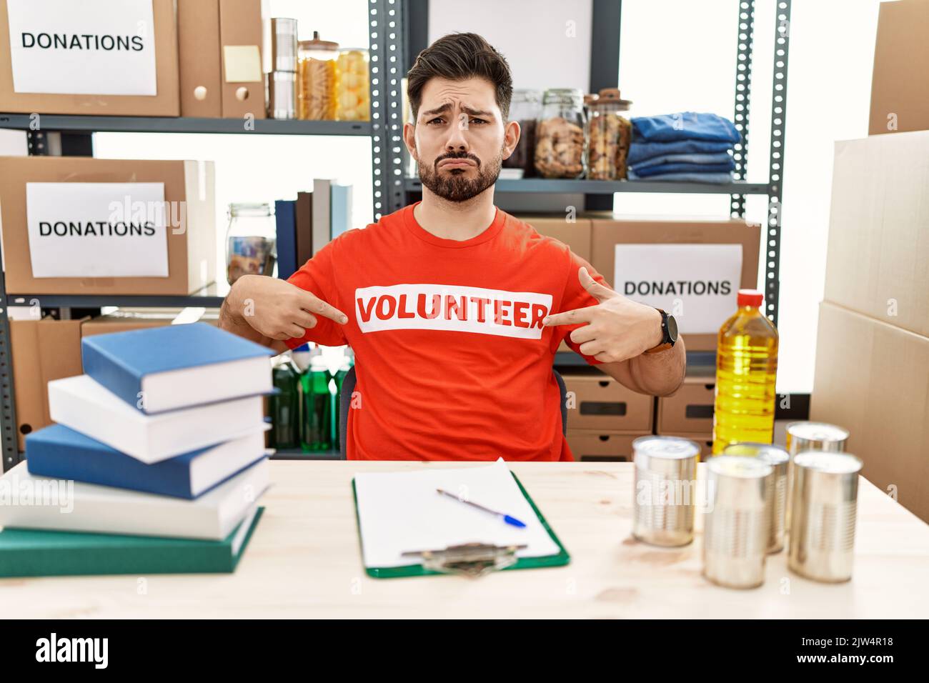 Young man with beard wearing volunteer t shirt at donations stand ...