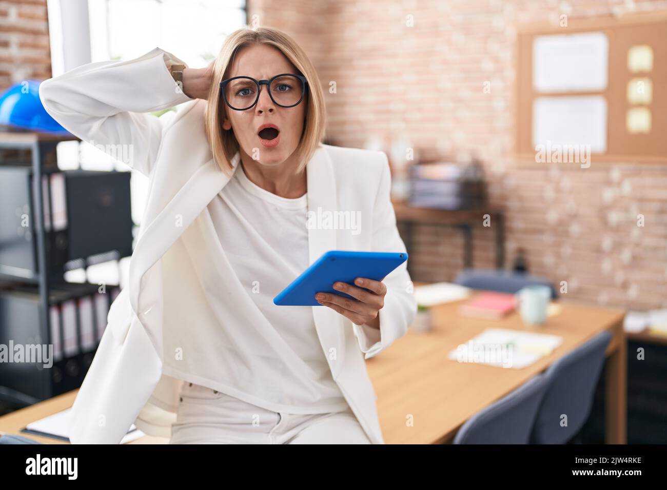 Young caucasian woman working at the office wearing glasses crazy and ...