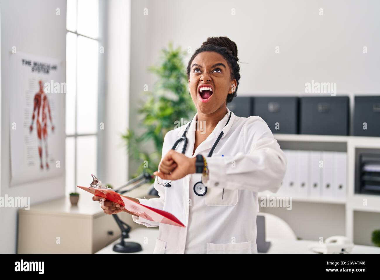 Young african american with braids wearing doctor uniform looking at ...