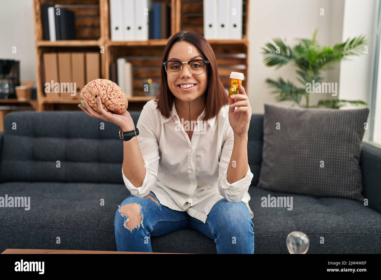 Young hispanic woman working on depression holding pills smiling with a ...