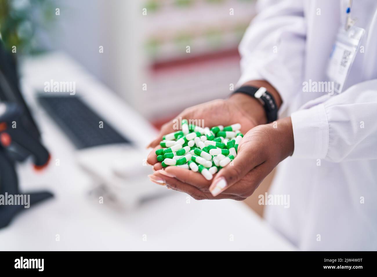 African american woman pharmacist holding pills at pharmacy Stock Photo ...
