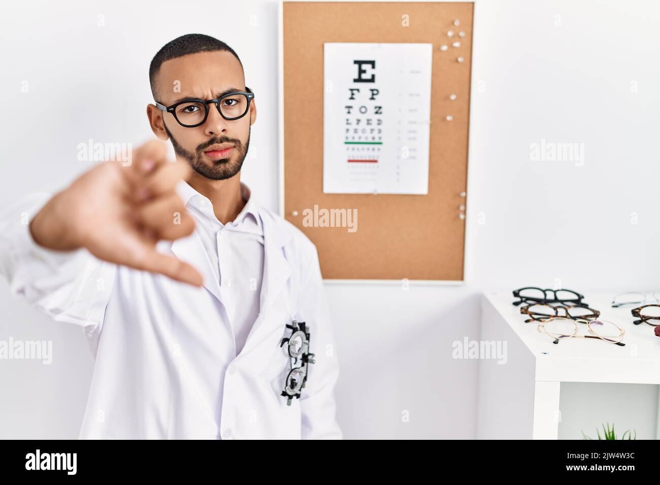 African american optician man standing by eyesight test looking unhappy ...