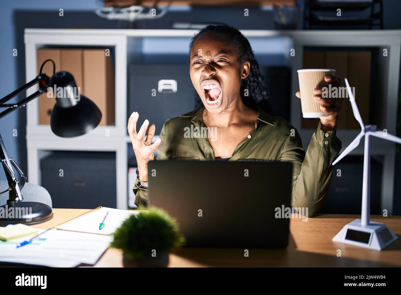 African woman working using computer laptop at night angry and mad ...