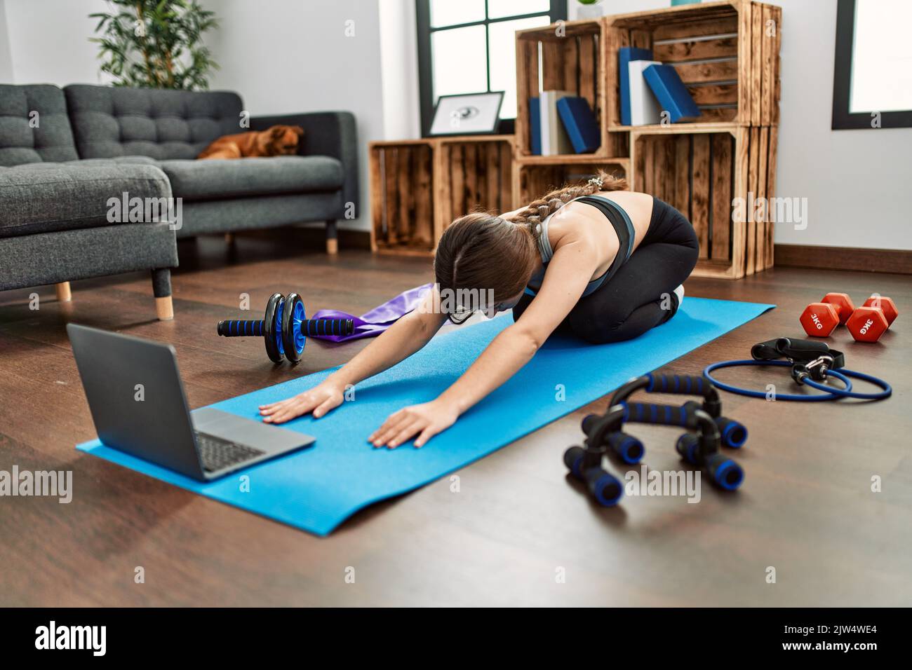 Young hispanic woman having online stretching class at home Stock Photo ...