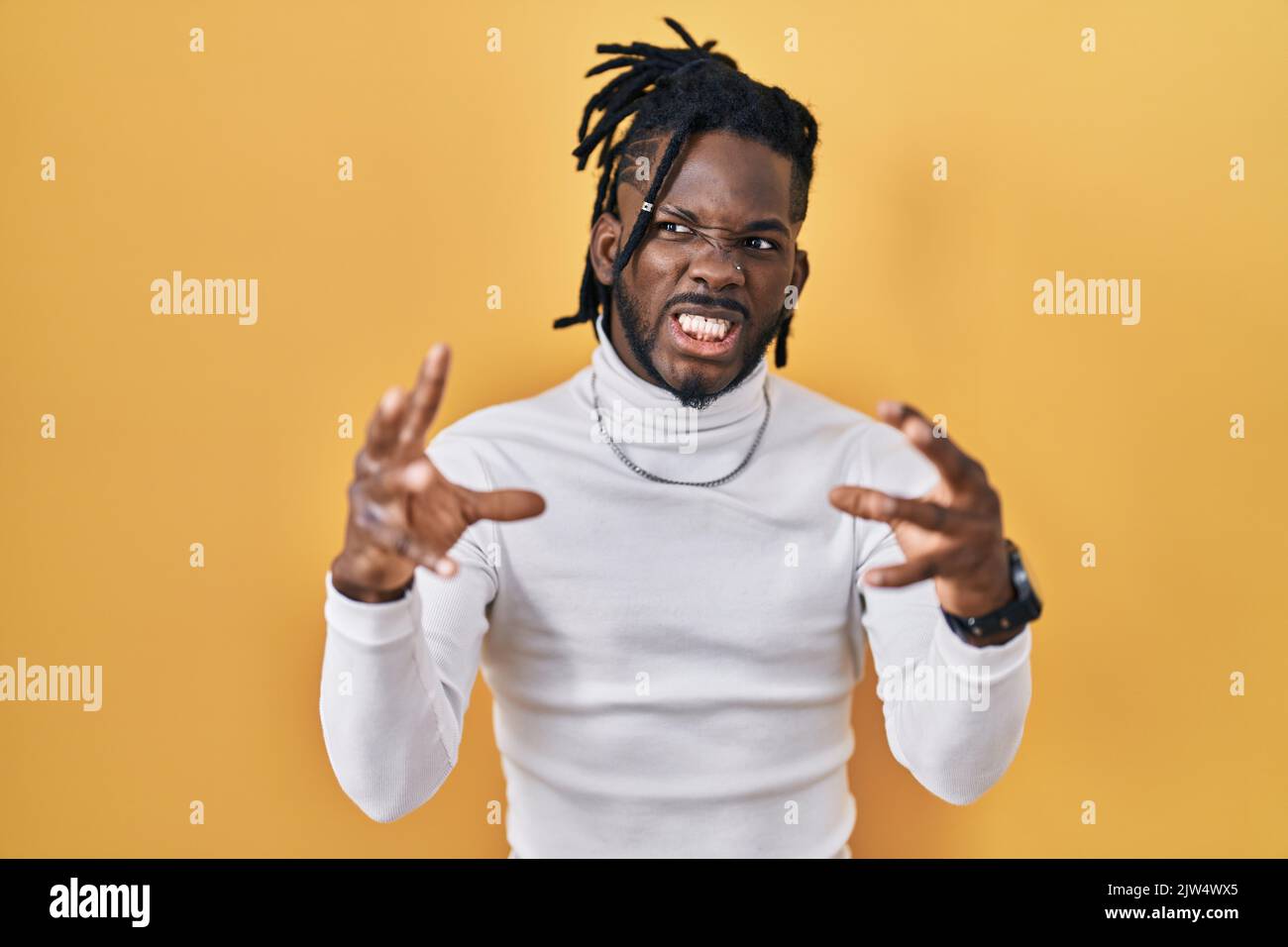 African man with dreadlocks wearing turtleneck sweater over yellow ...