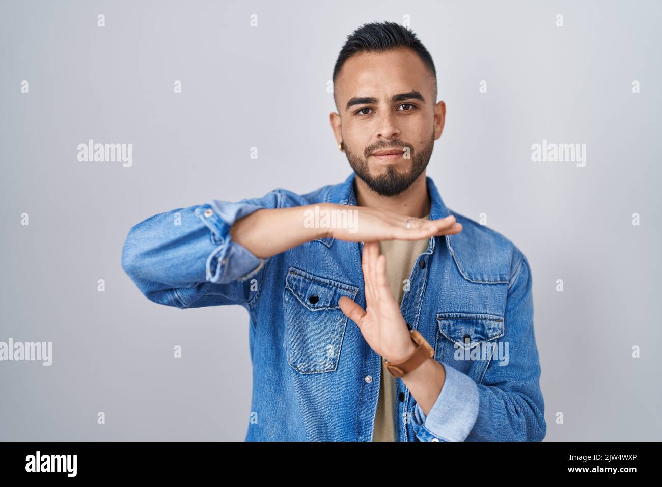 Young hispanic man standing over isolated background doing time out ...
