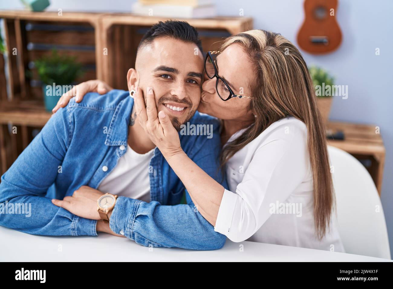 Man and woman mother and son sitting on table kissing at home Stock ...
