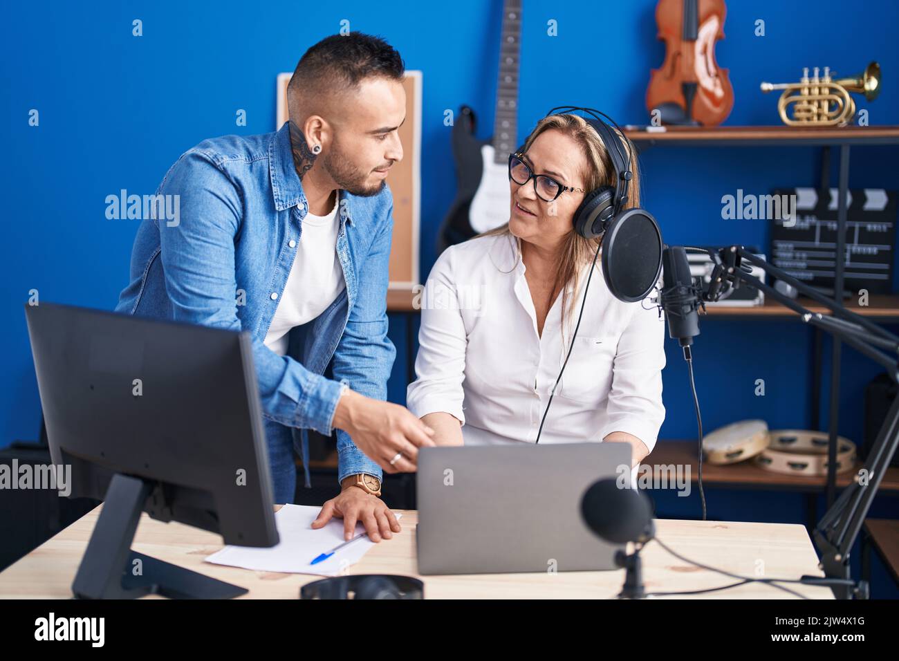 Man and woman musicians listening to music speaking at music studio ...