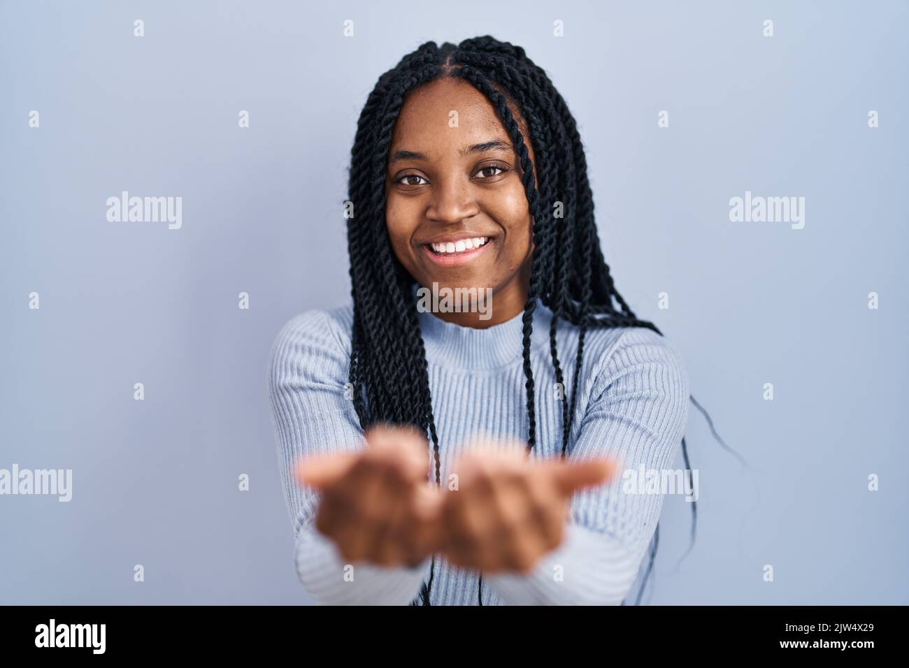 African american woman standing over blue background smiling with hands ...