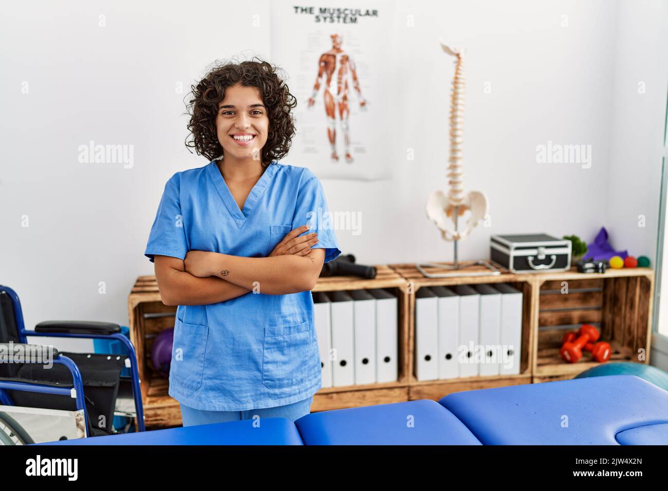 Young hispanic woman wearing physio therapist uniform standing with ...