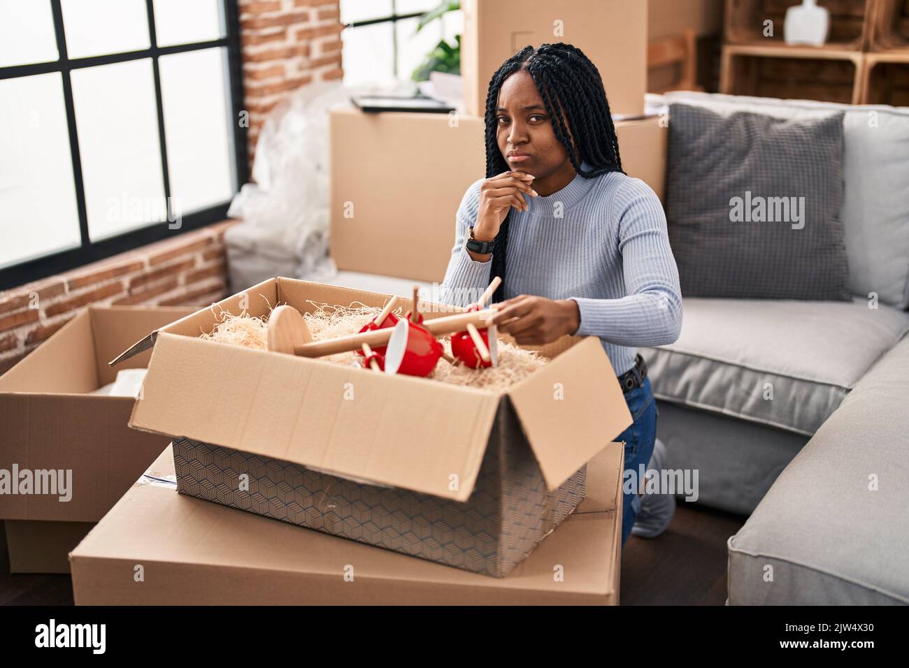 African american woman moving to a new home opening boxes serious face ...