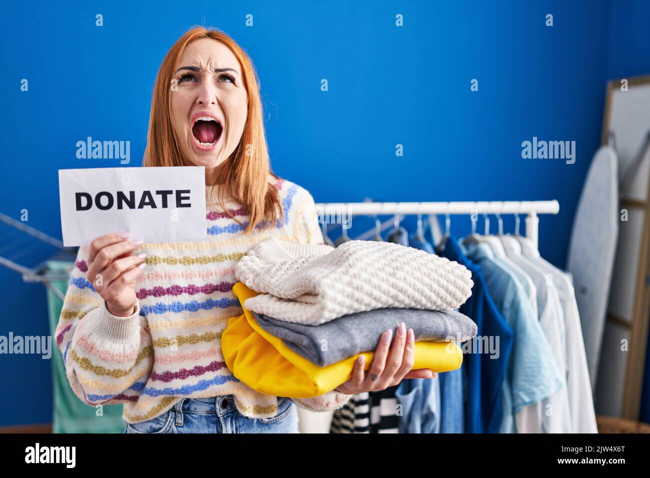 Young woman holding donations for charity angry and mad screaming ...