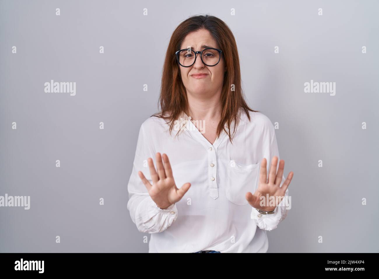 Brunette woman standing over white isolated background moving away ...
