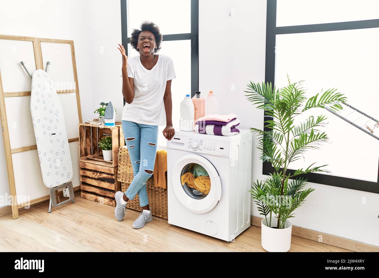 African young woman doing laundry at home celebrating victory with ...