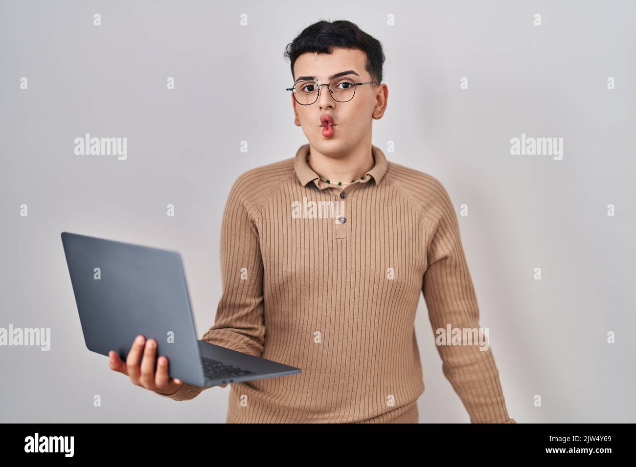 Non binary person using computer laptop making fish face with lips ...