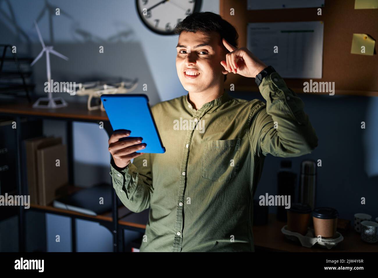 Non binary person using touchpad device at night smiling pointing to ...