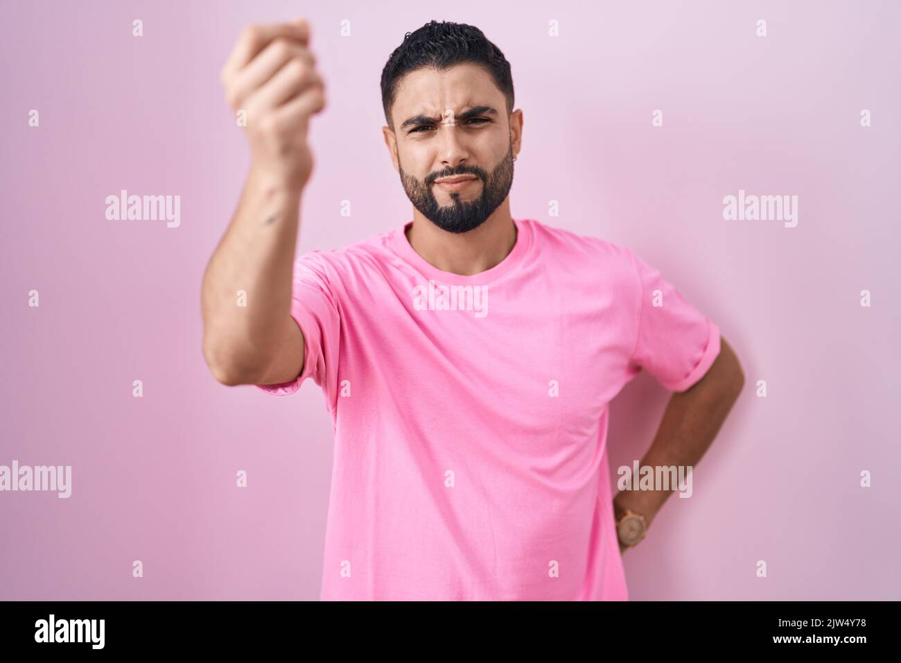 Hispanic young man standing over pink background doing italian gesture ...