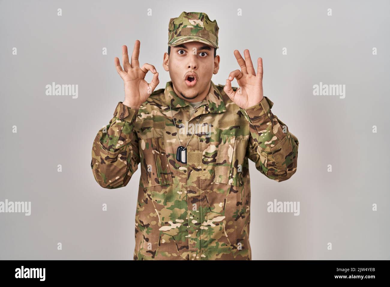 Young arab man wearing camouflage army uniform looking surprised and ...