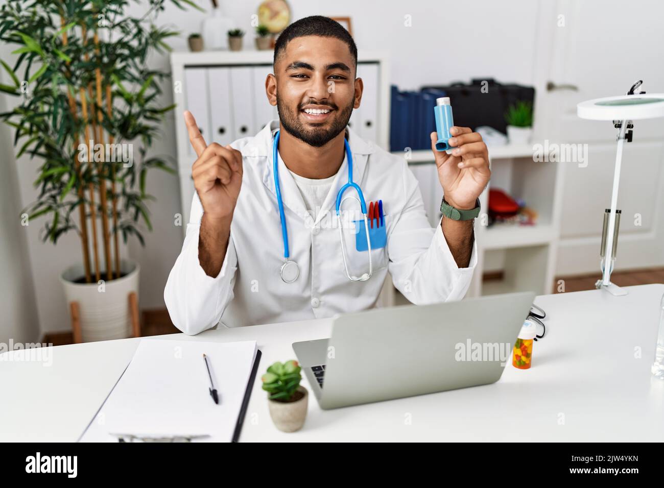 Young indian doctor holding medical asthma inhaler at the clinic ...