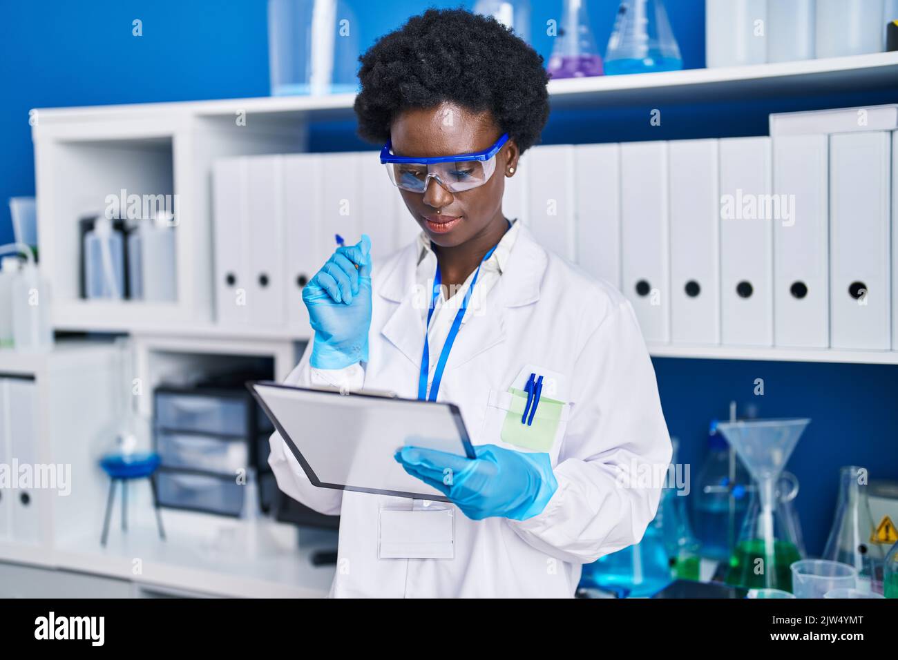 Young african american woman scientist reading document at laboratory ...