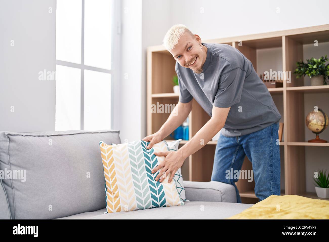 Young caucasian man smiling confident organizing sofa at home Stock ...
