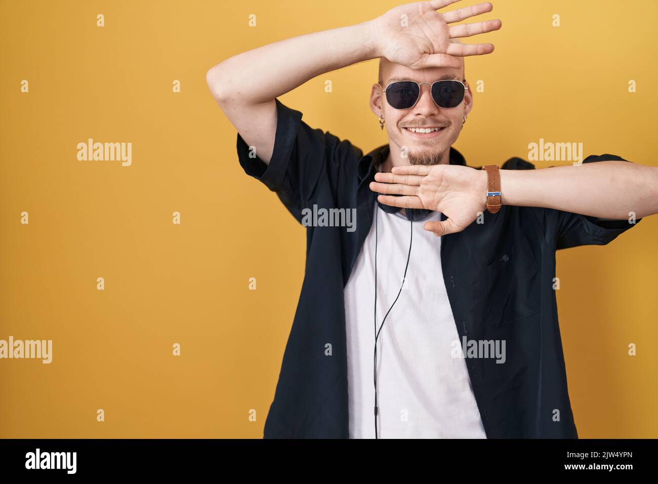 Young caucasian man wearing sunglasses standing over yellow background ...