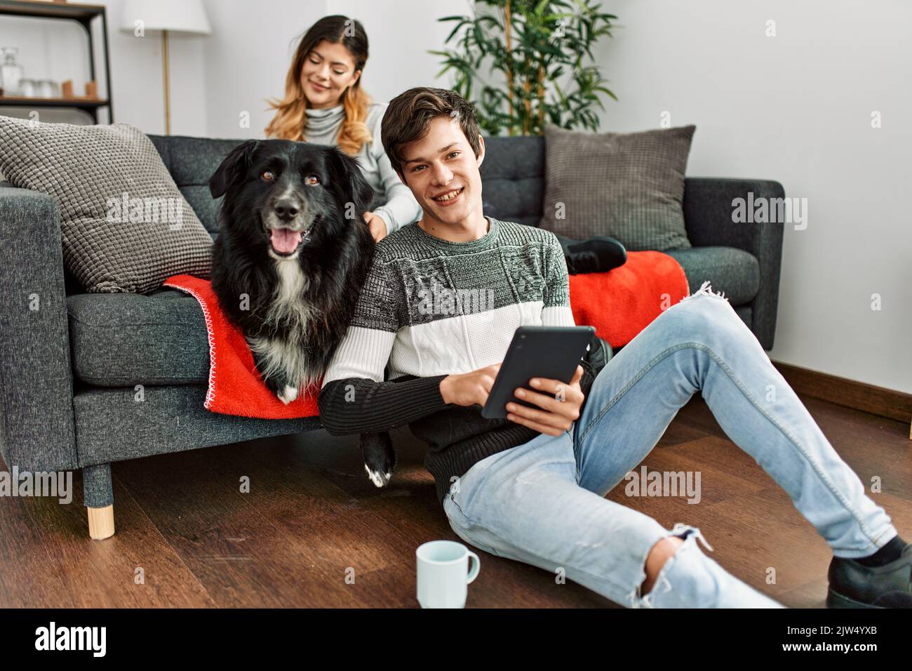 Young caucasian couple smiling happy with dog using touchpad at home ...