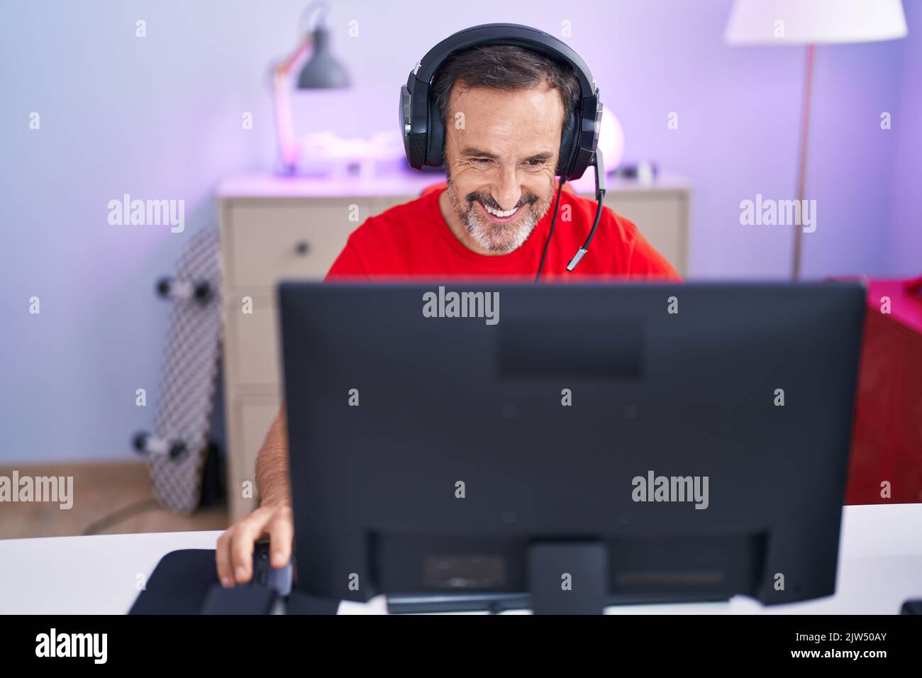Middle age man streamer playing video game using computer at gaming ...