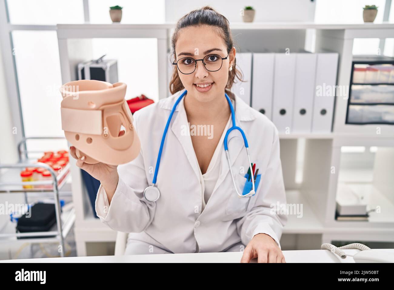 Young hispanic doctor woman holding cervical neck collar looking ...