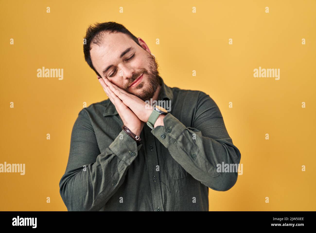 Plus size hispanic man with beard standing over yellow background ...