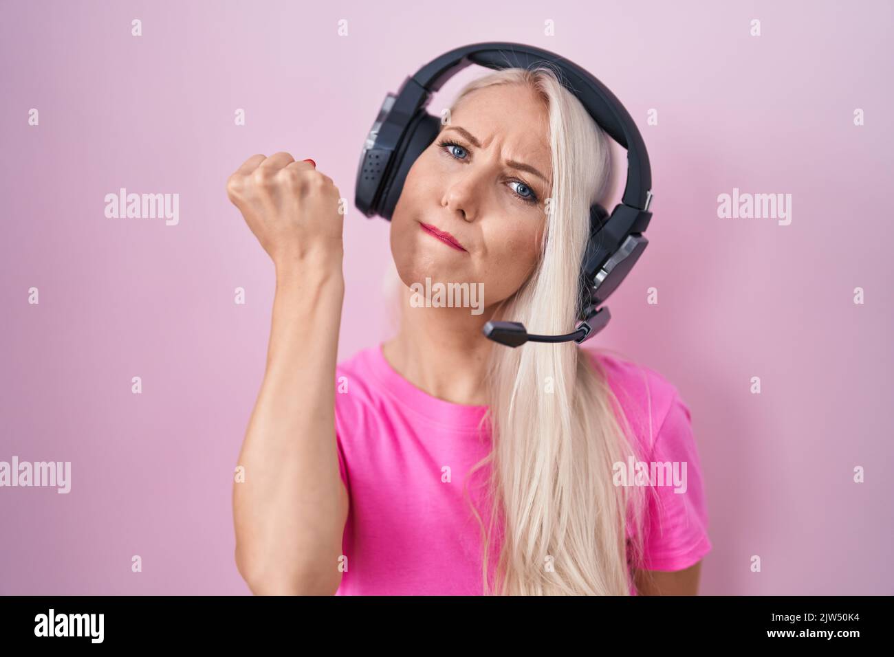 Caucasian woman listening to music using headphones angry and mad ...