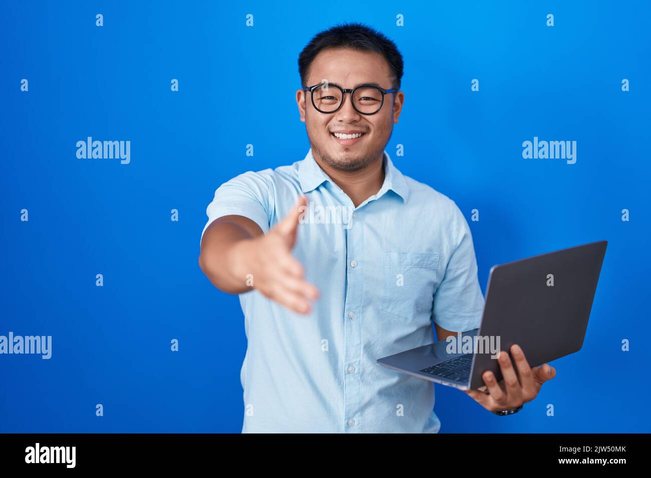 Chinese young man using computer laptop smiling friendly offering ...
