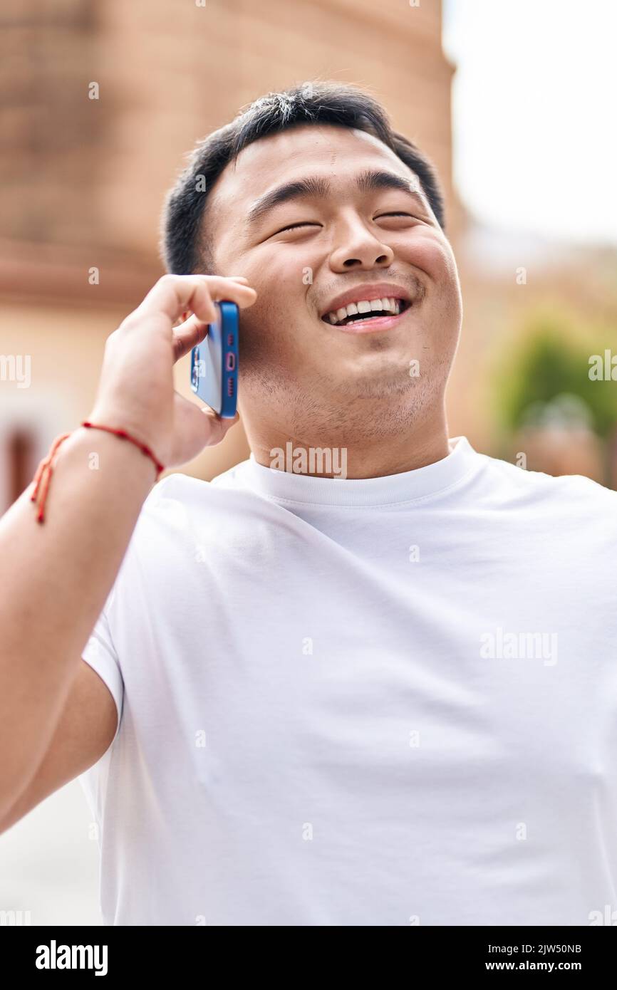 Young chinese man smiling confident talking on the smartphone at street ...