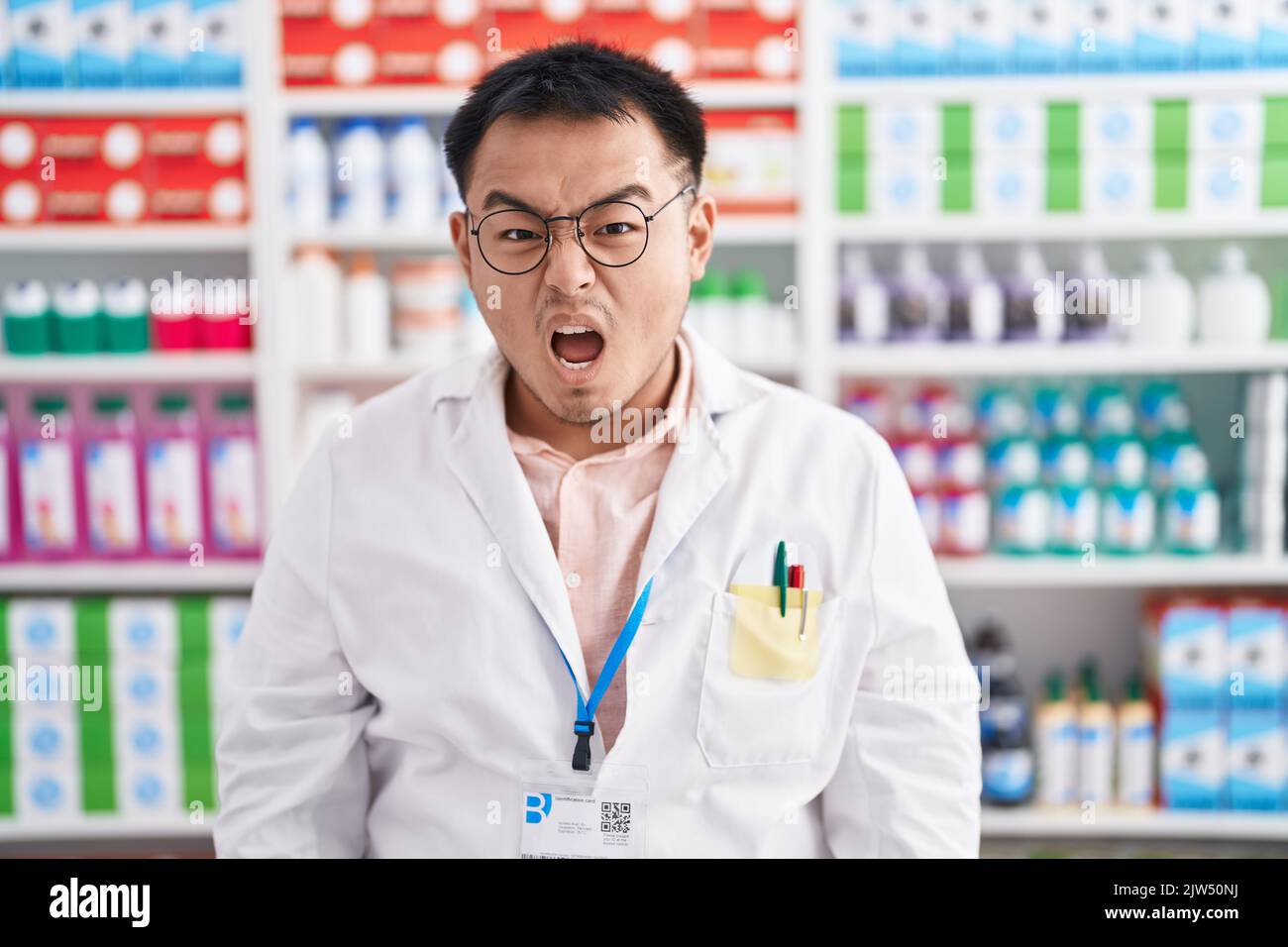 Chinese young man working at pharmacy drugstore angry and mad screaming ...