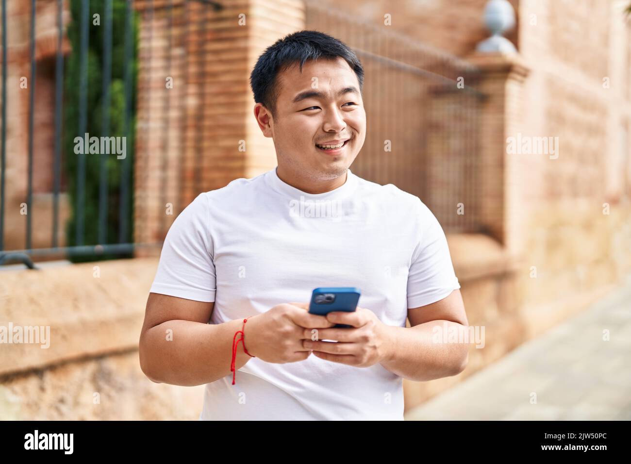 Young chinese man smiling confident using smartphone at street Stock ...