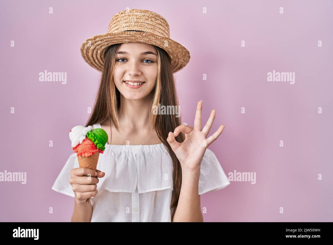 Teenager girl holding ice cream smiling positive doing ok sign with ...