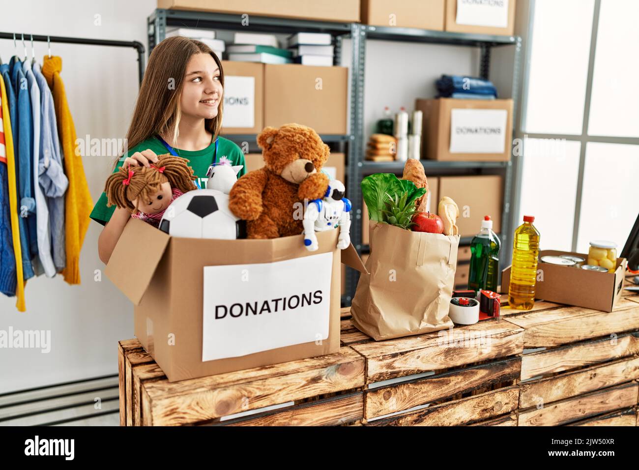 Adorable girl wearing volunteer uniform working at charity center Stock ...