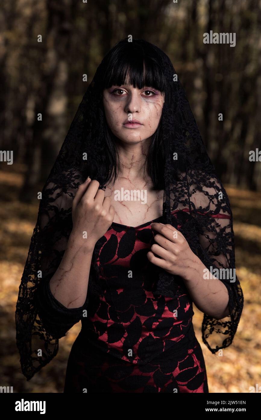 A Vertical shot of a Caucasian pretty female in a gothic style black ...