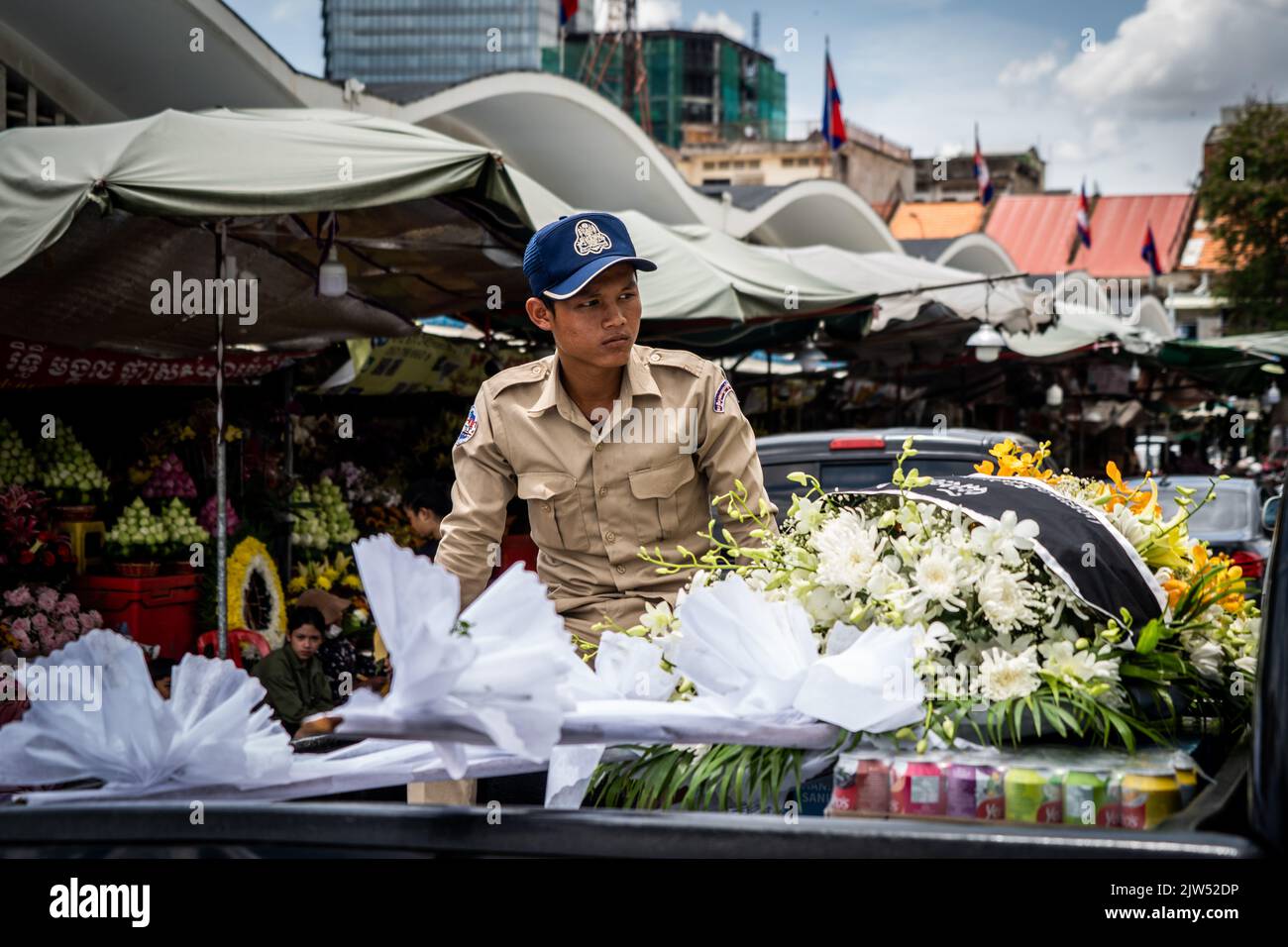 A policeman holds onto flower arrangements on the back of a truck ...
