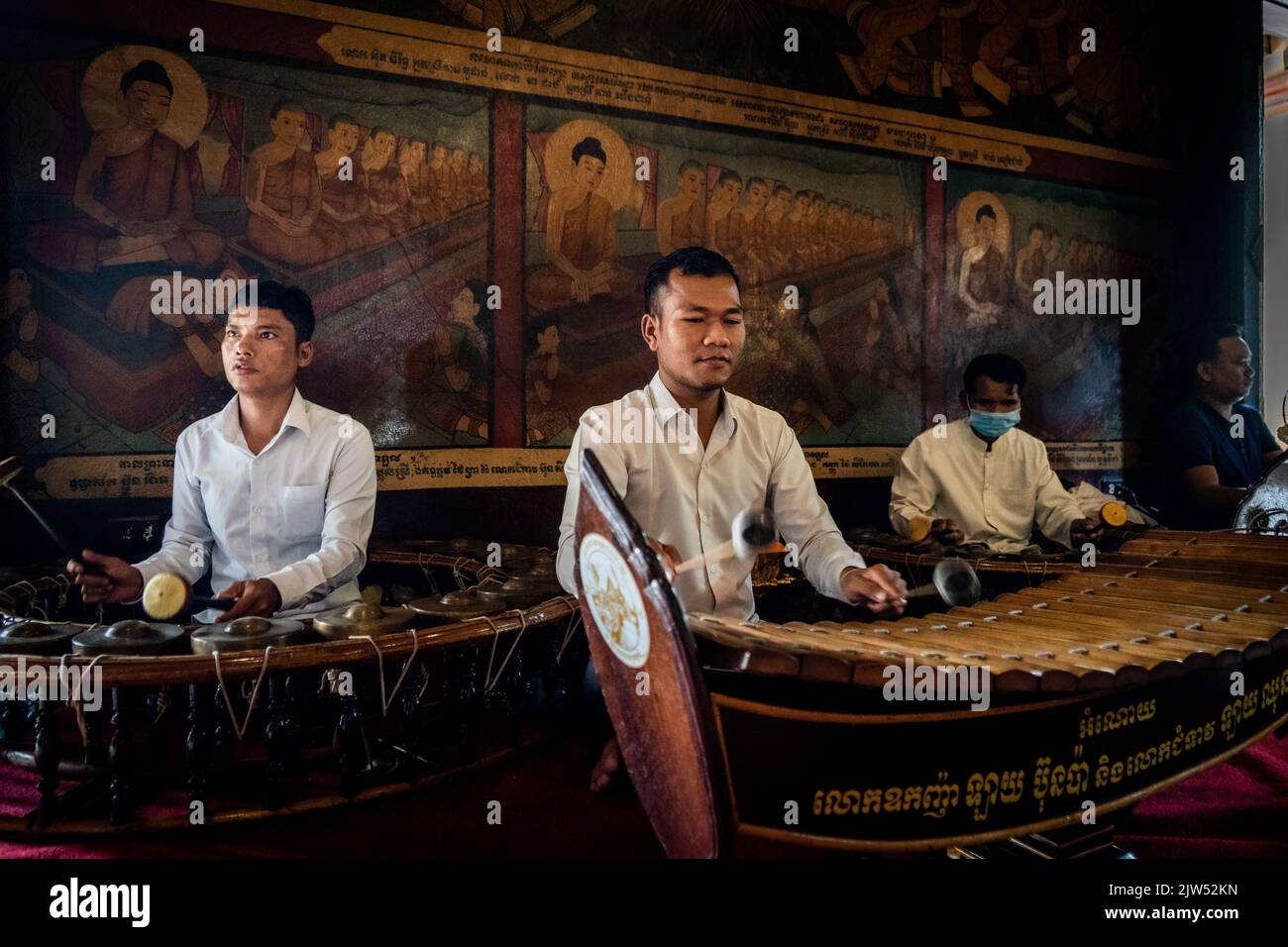 A band plays traditional Khmer musical instruments while people come to ...