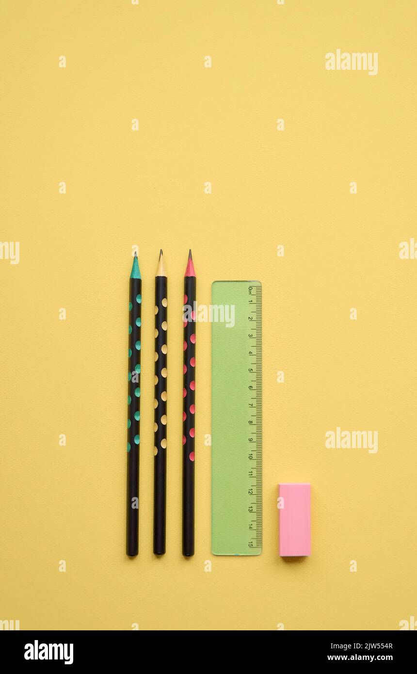 Pencils, ruler and rubber on yellow background, flatlay. Back to school ...