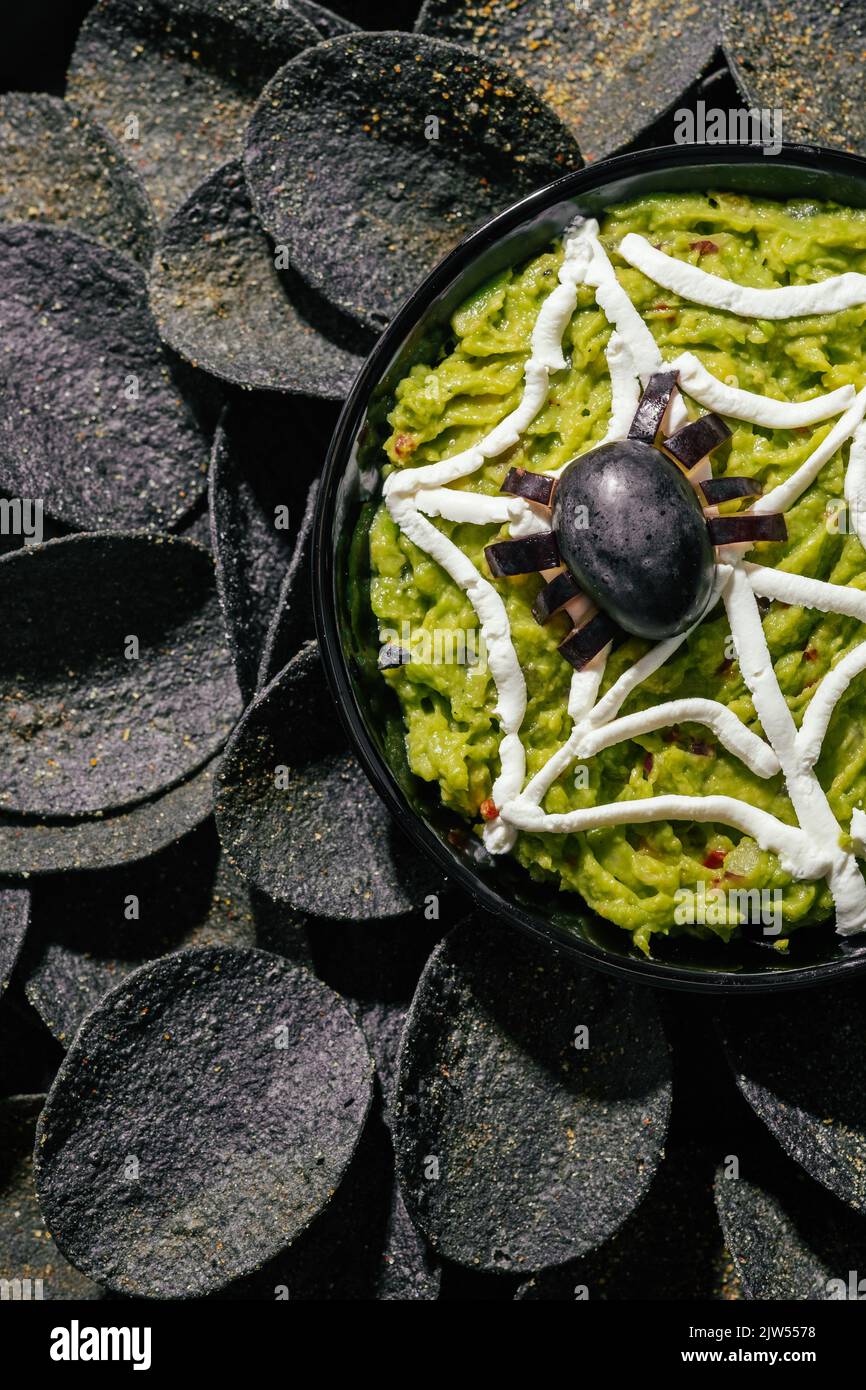 Spooky Halloween black potato chips with guacamole dip Stock Photo - Alamy